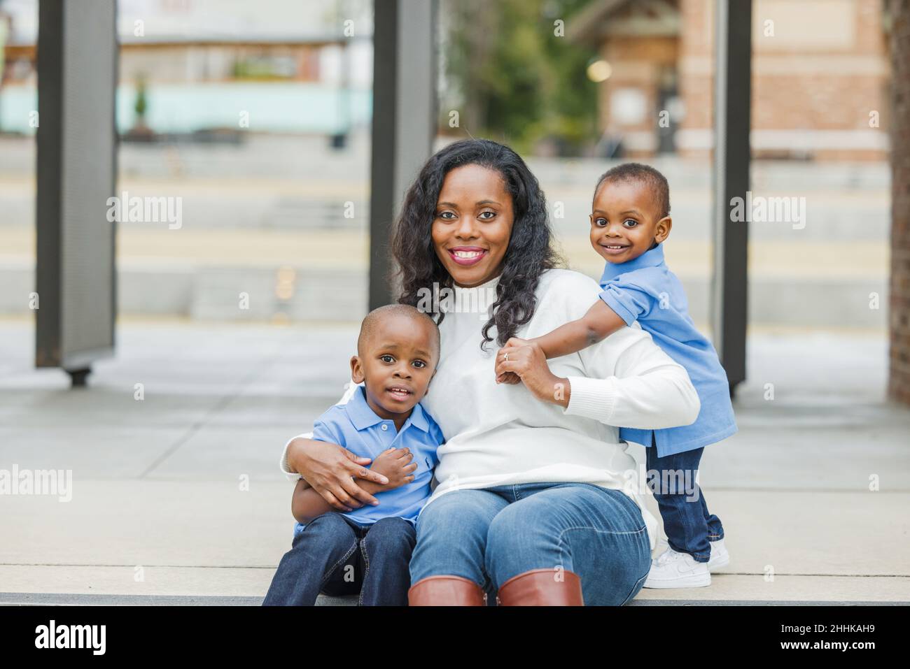 A mom with long hair sitting outside with her two young sons Stock ...