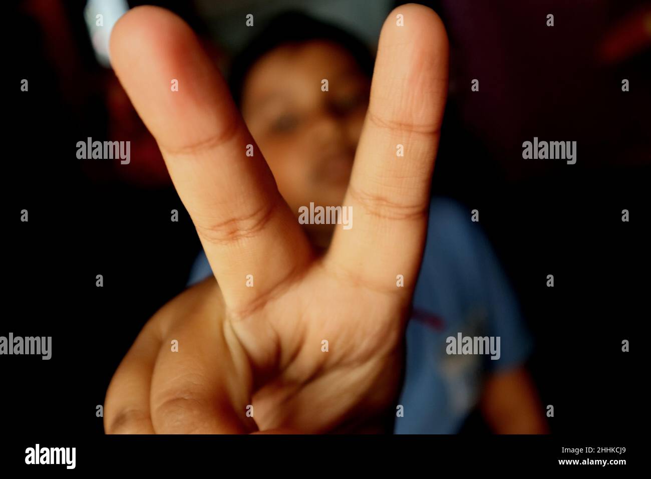 A kid showing two fingers and hand with a smiling face Stock Photo - Alamy