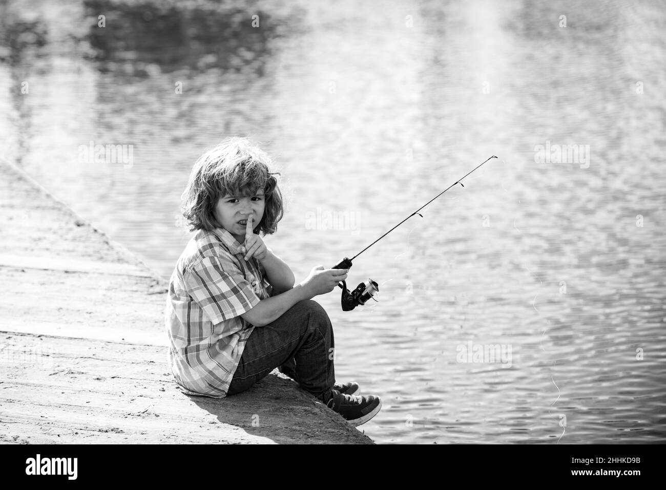 Serious, little boy child is fishing on the river with a fishing rod ...