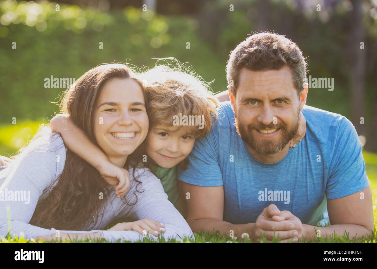 Cute family portrait hugging and embracing. Family lying on grass in ...