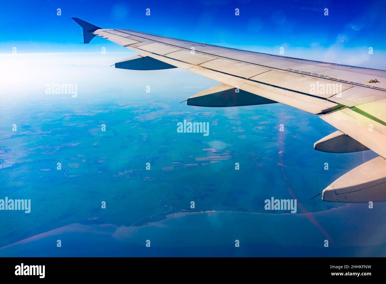 View from the airplane window at a beautiful blue clear sky, earth, sea ...