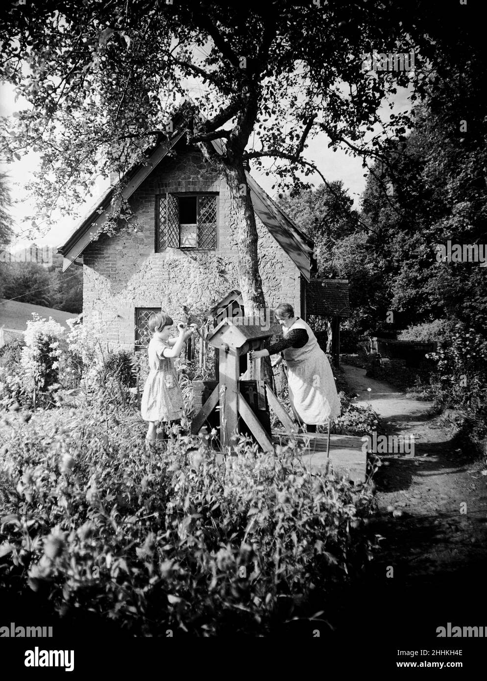 Mother and daughter winding up the bucket from the well in their ...