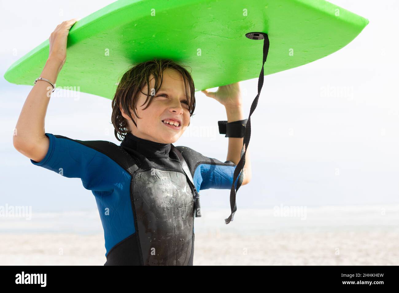 Boy (8-9) carrying bodyboard on beach Stock Photo - Alamy