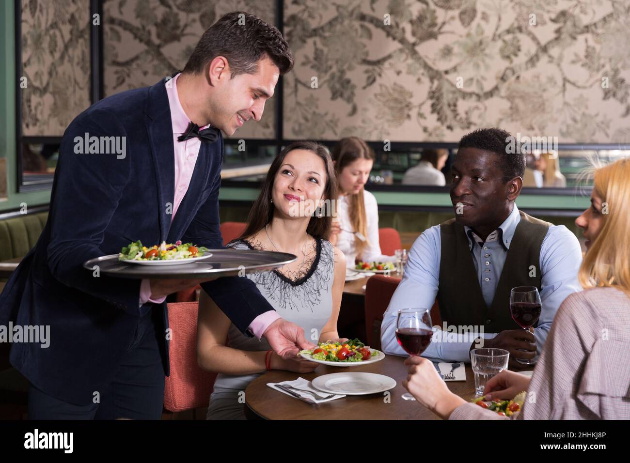 Polite waiter bringing dishes to guests Stock Photo - Alamy