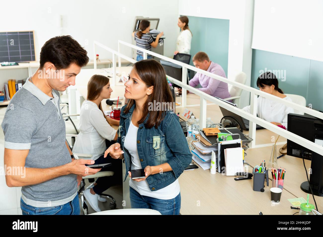 Friendly male and female colleagues exchanging phone numbers in modern ...