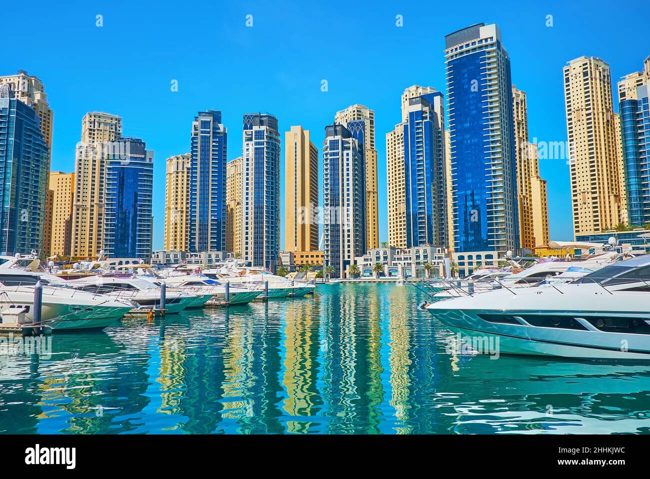 The modern white yachts and boats in port of Dubai Marina, lined with ...