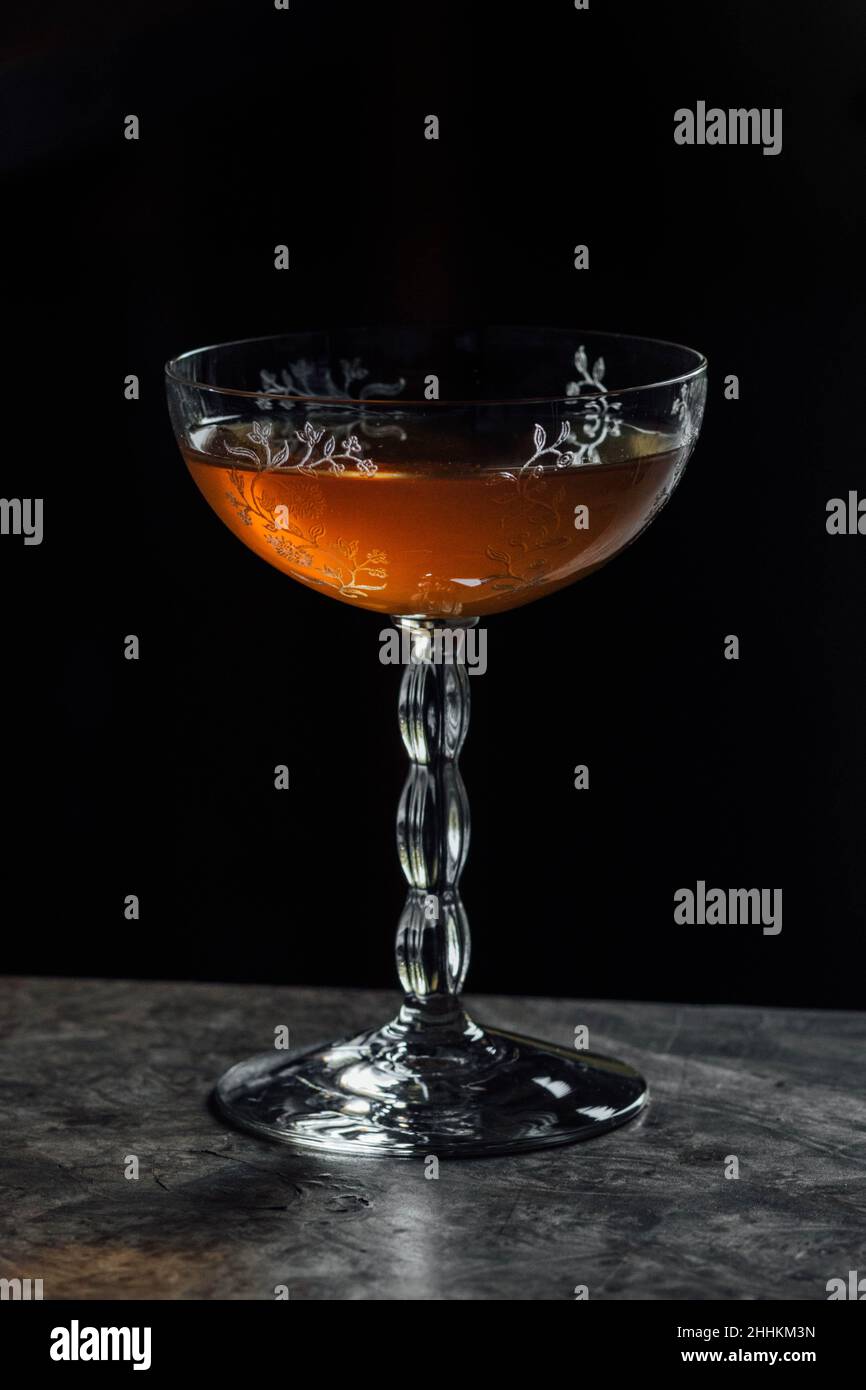 amber colored Emerson cocktail in vintage etched glassware Stock Photo ...
