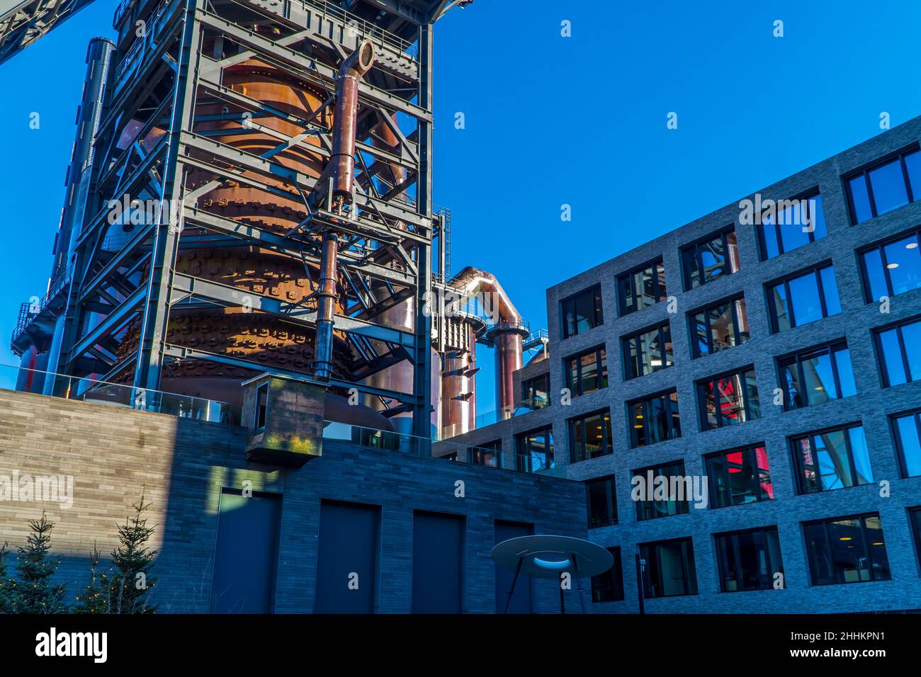 Low angle shot of reconverted steel chimney tower and modern buildings ...