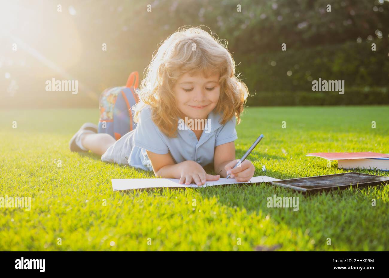 Little boy reading a book and writing notes in copybook in summer ...