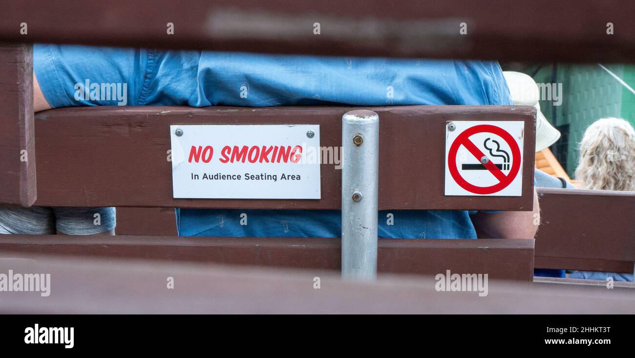 Closeup of a NO SMOKING sign on the back of a wooden bench at an ...