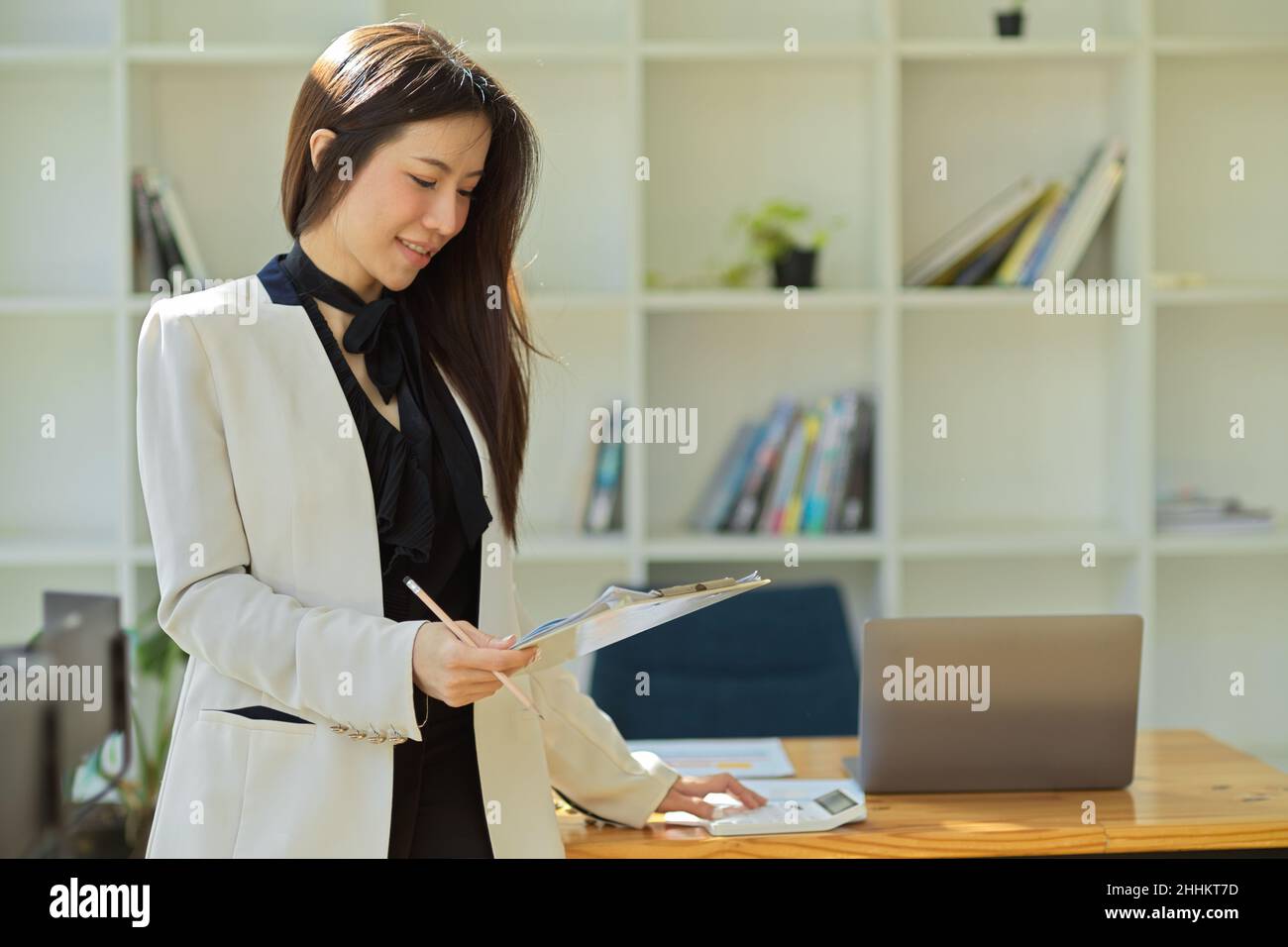 Beautiful executive female manager standing in the office and looking ...