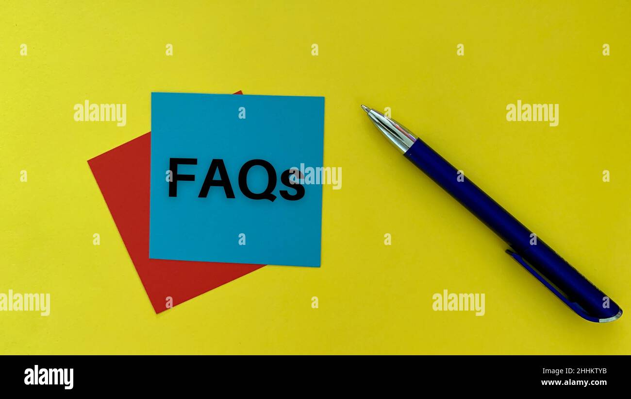 FAQs text on blue post it note with pen and yellow background. Business ...