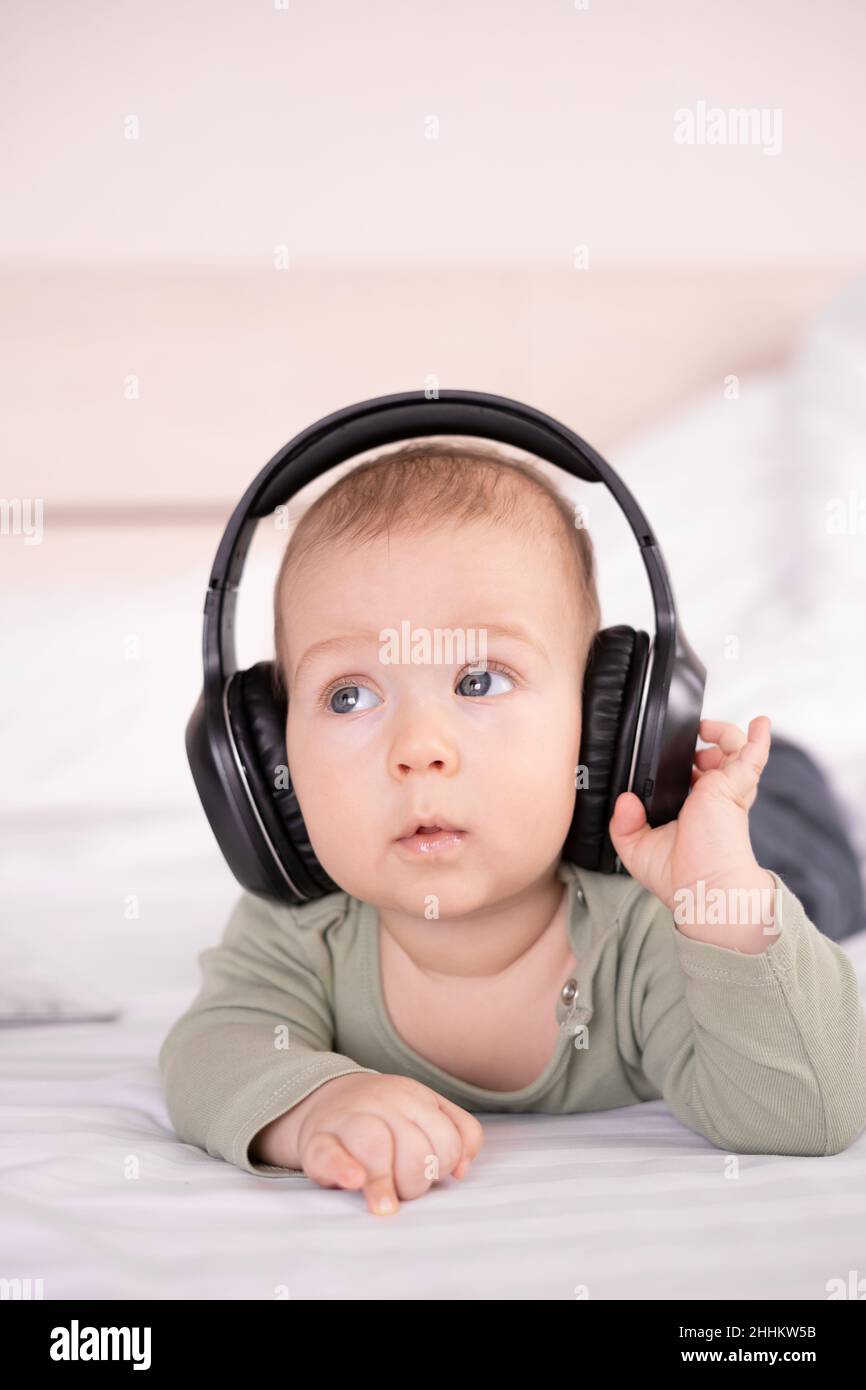 positive baby lying on a white background in headphones listening to ...