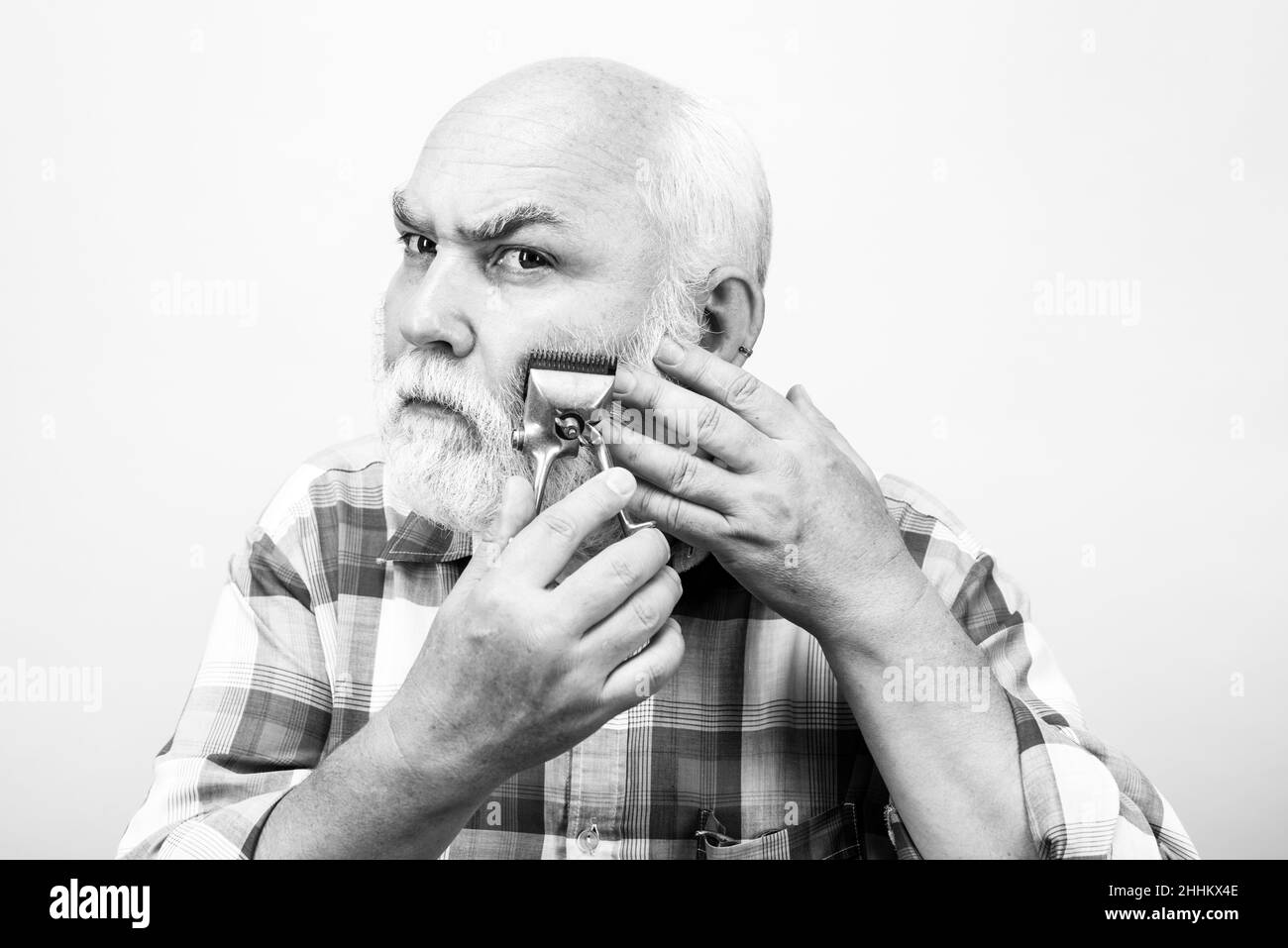 Old gray man cut bear with hair clipper. Portrait of barber hold old ...