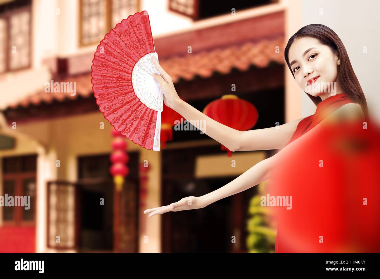 Asian Chinese woman in a cheongsam dress holding fan with open palm ...