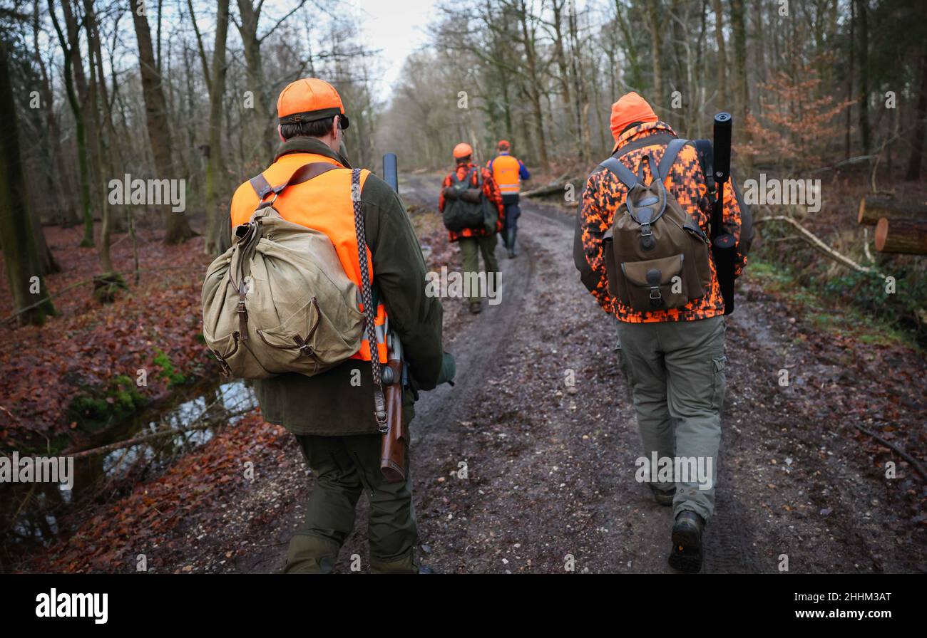 Drage, Germany. 15th Jan, 2022. A group of hunters walks along a dirt ...