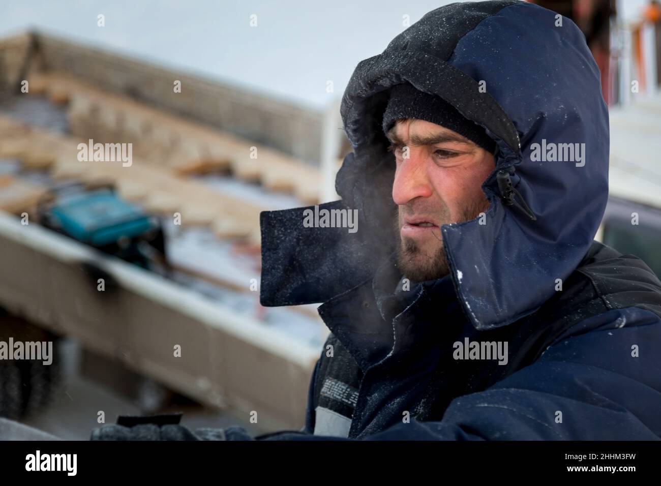 Close-up of the face of a worker in a blue jacket at the workplace ...