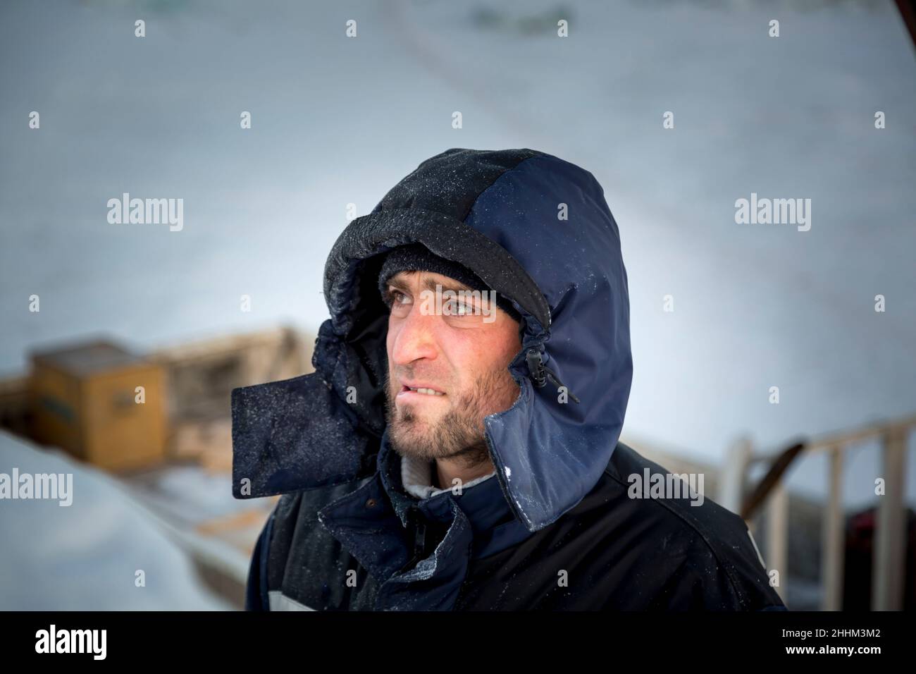 Close-up of the face of a worker in a blue jacket at the workplace ...
