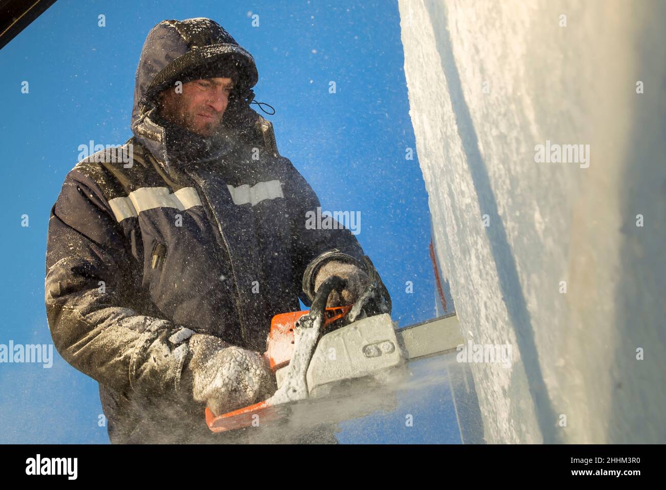A worker with a chainsaw in his hands on the installation of the ice ...