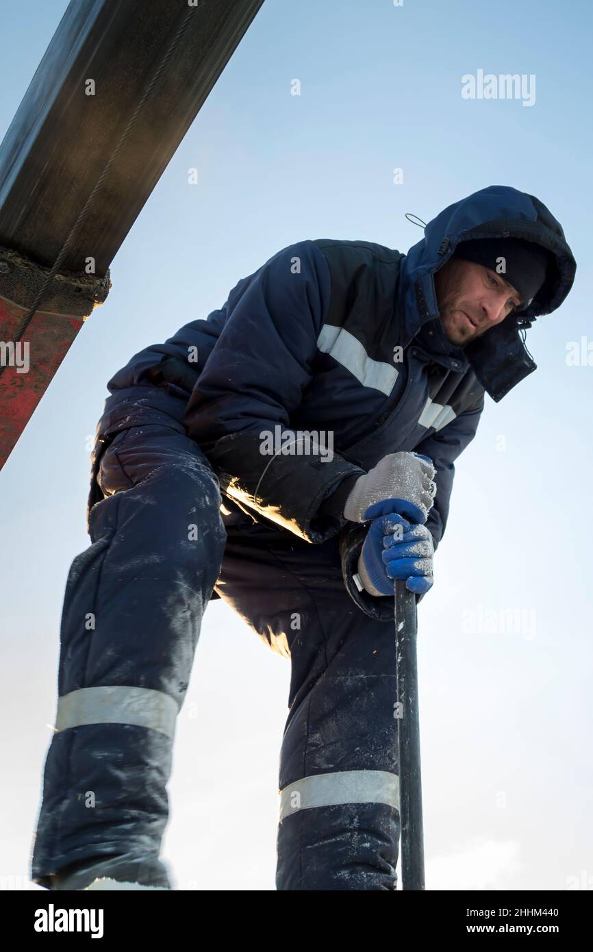 Portrait of a worker moving an ice block with a metal crowbar on an ice ...