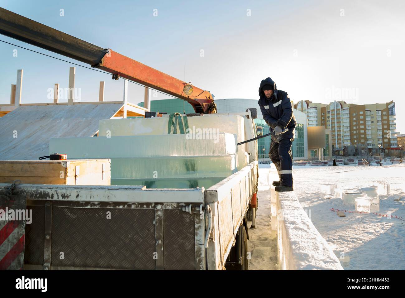 Portrait of a worker moving an ice block with a metal crowbar on an ice ...