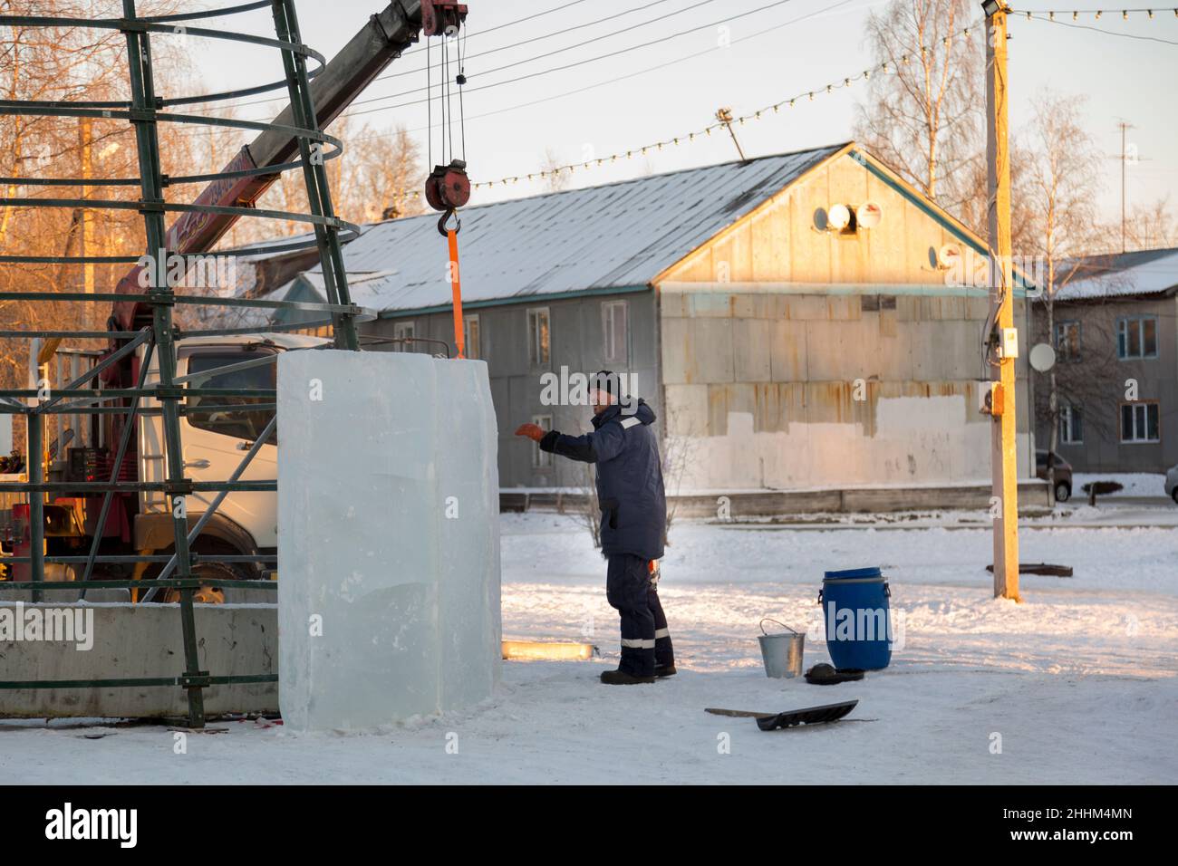 An ice town builder in a blue jacket encloses a Christmas tree under ...