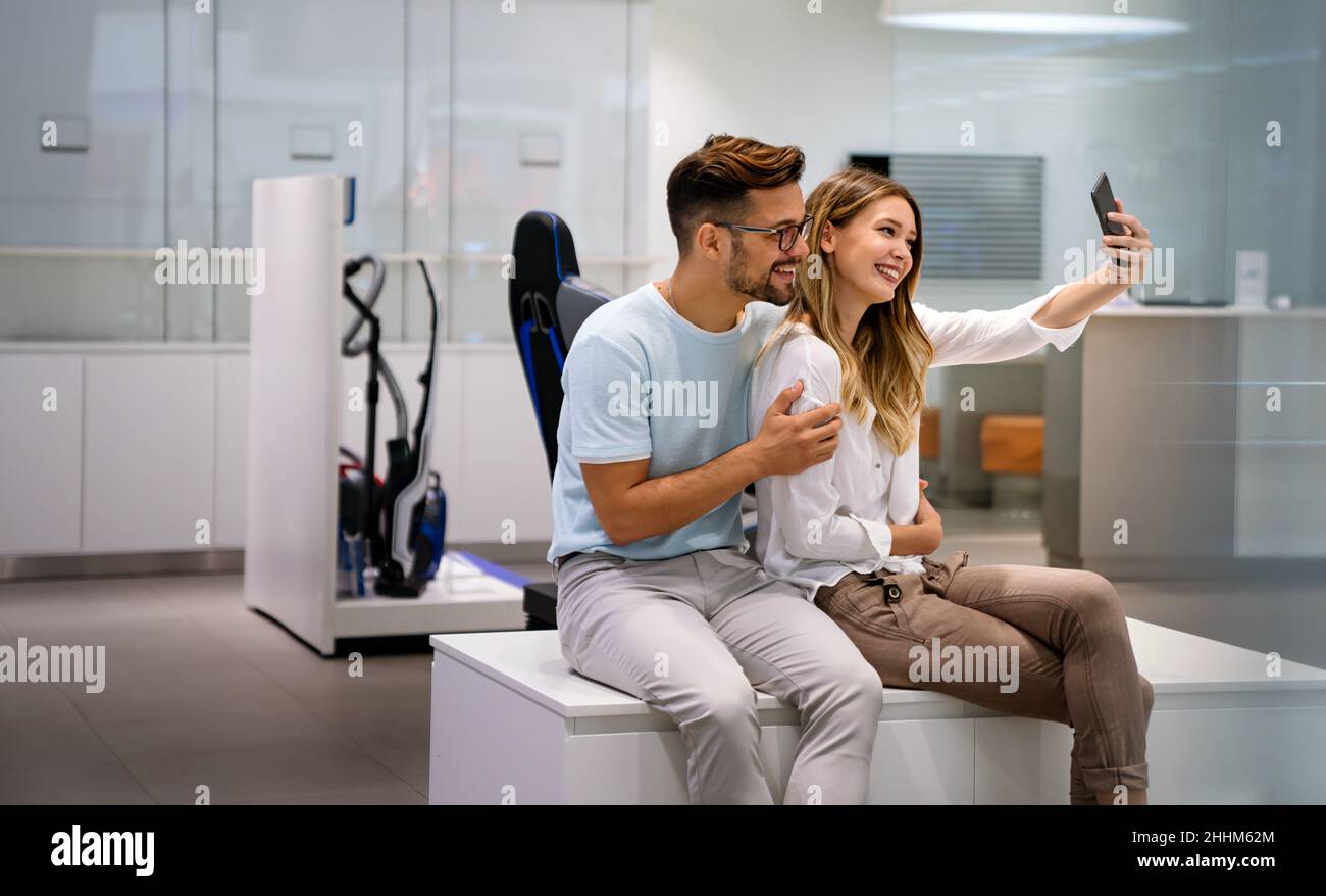 Portrait of a happy couple making a selfie in a tech store. Technology ...