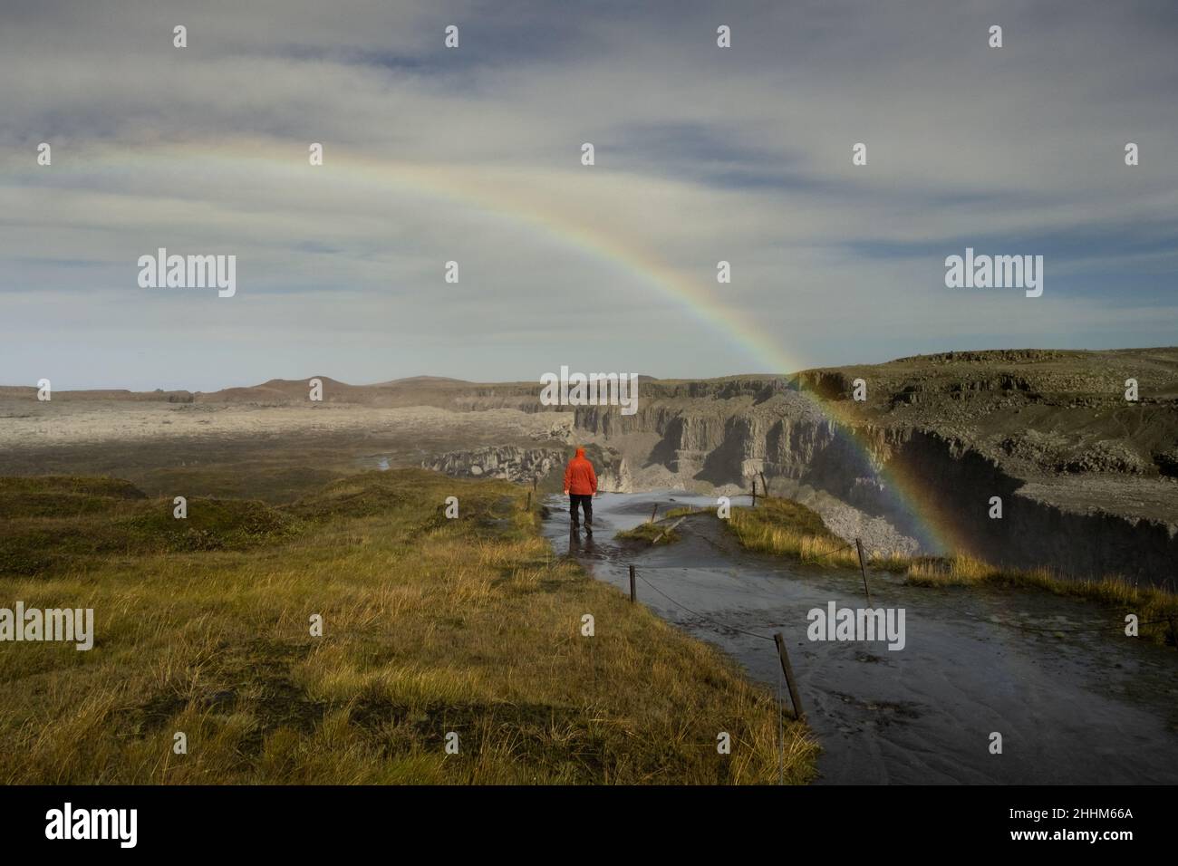 A man in a red jacket is standing under the rainbow Stock Photo - Alamy
