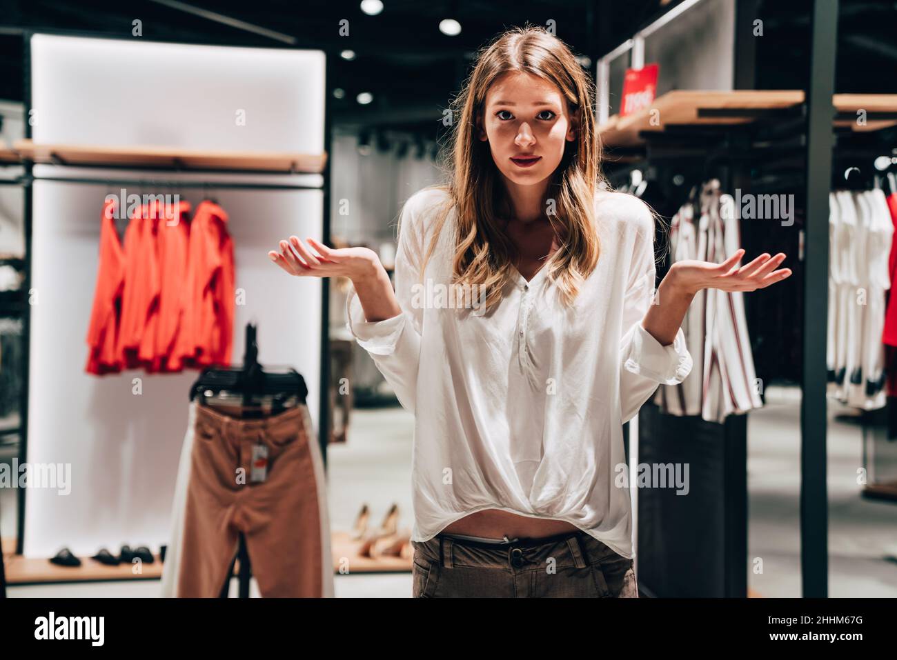 Woman having difficulties choosing dress at a boutique. Shopping ...