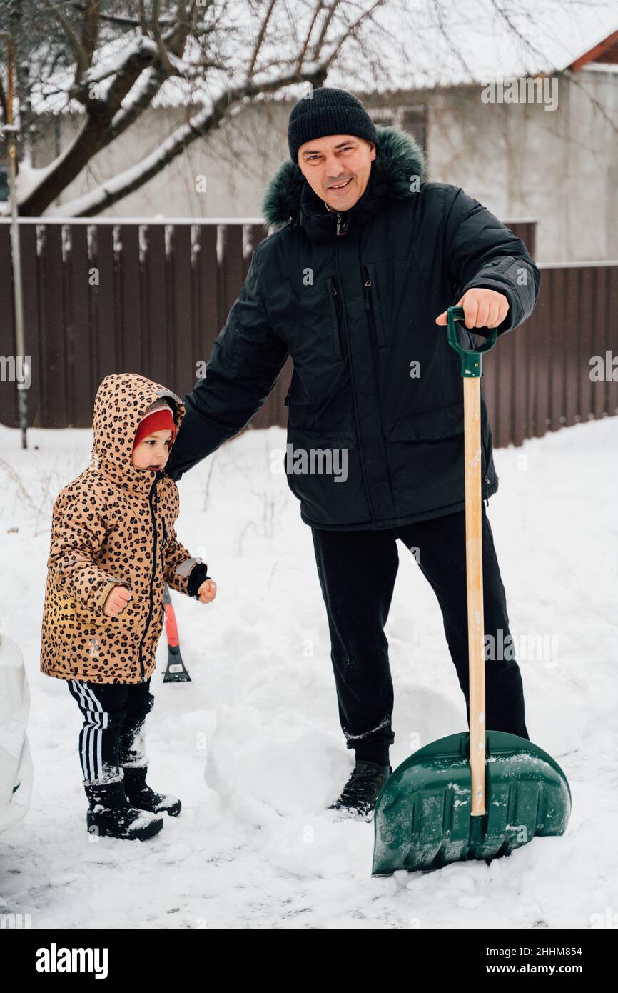 Snow collapse. Senior man with child cleaning snow at winter weather ...
