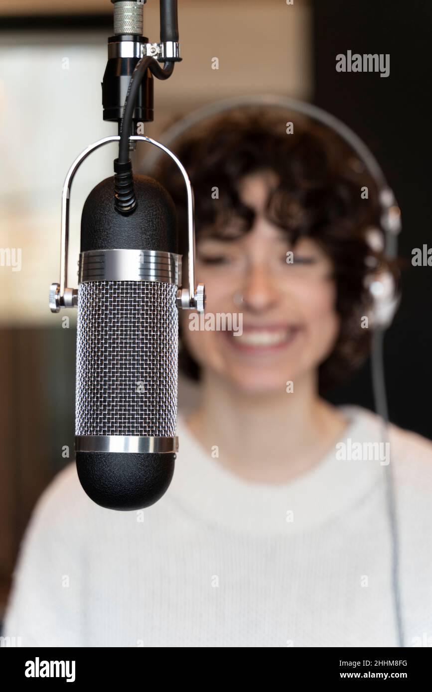 Defocused young curly hair singer woman recording a song in a real ...