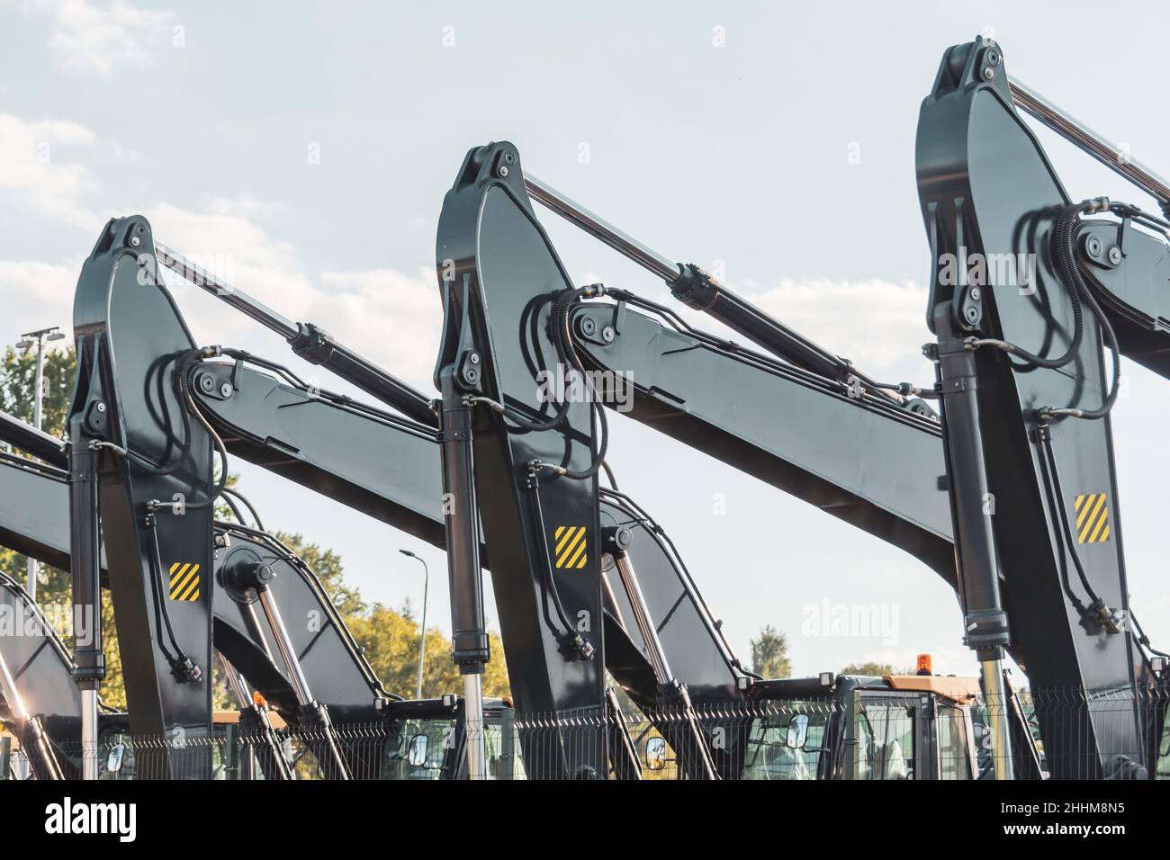 Row of booms and buckets of excavators Stock Photo - Alamy