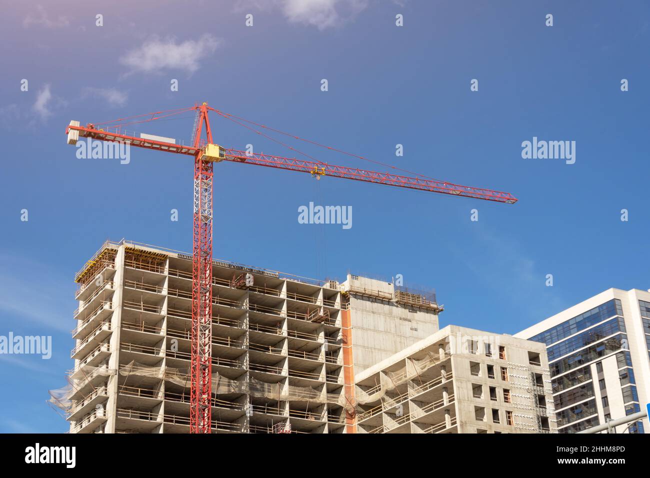 View of a building with high construction cranes and nearby a glass ...