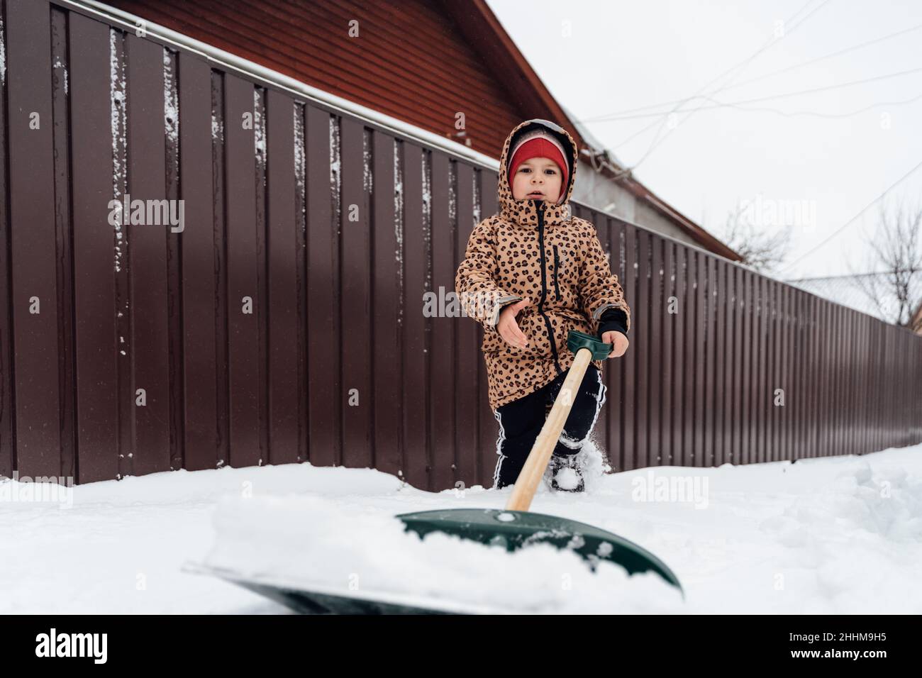 Low angle view of the little kid girl helping to clean pathway from ...