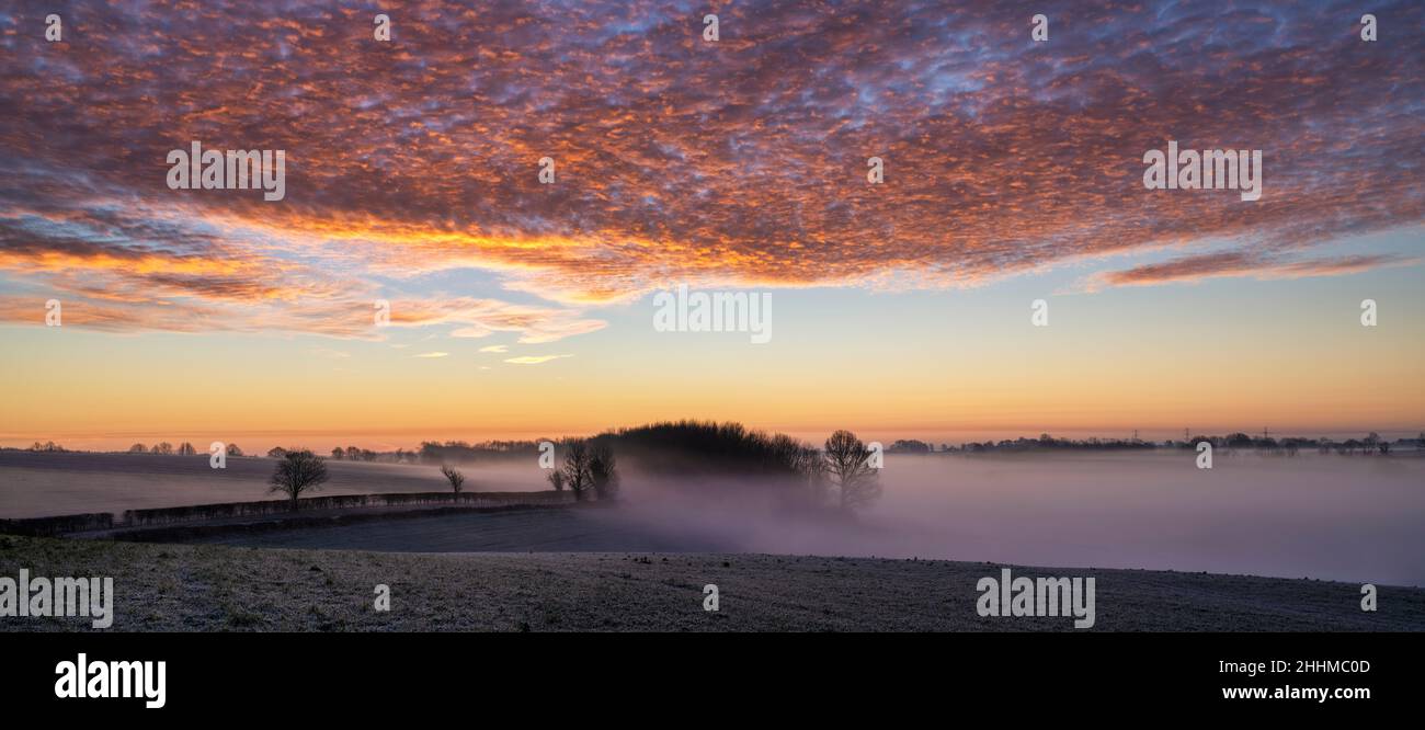 Winter red sky and mist just before sunrise in the frosty cotswold ...