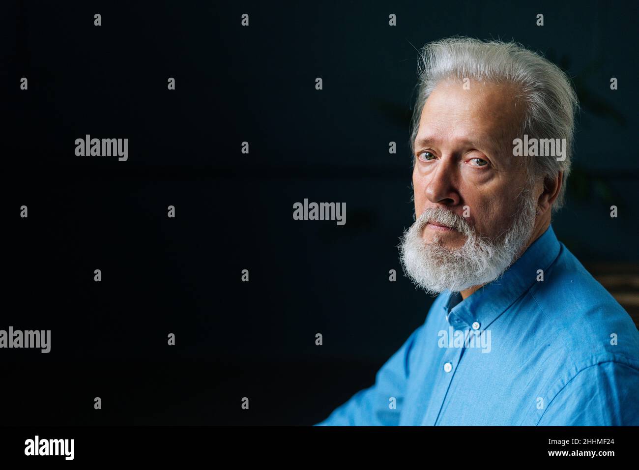 Studio portrait of sad gray-haired senior man unemotionally looking at ...