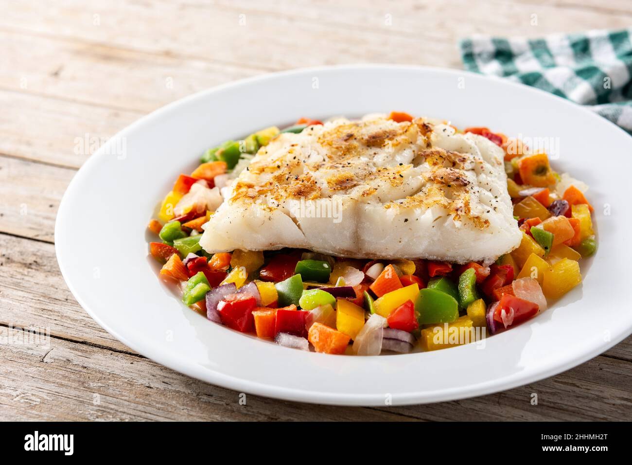 Grilled cod with vegetables in plate on wooden table Stock Photo - Alamy