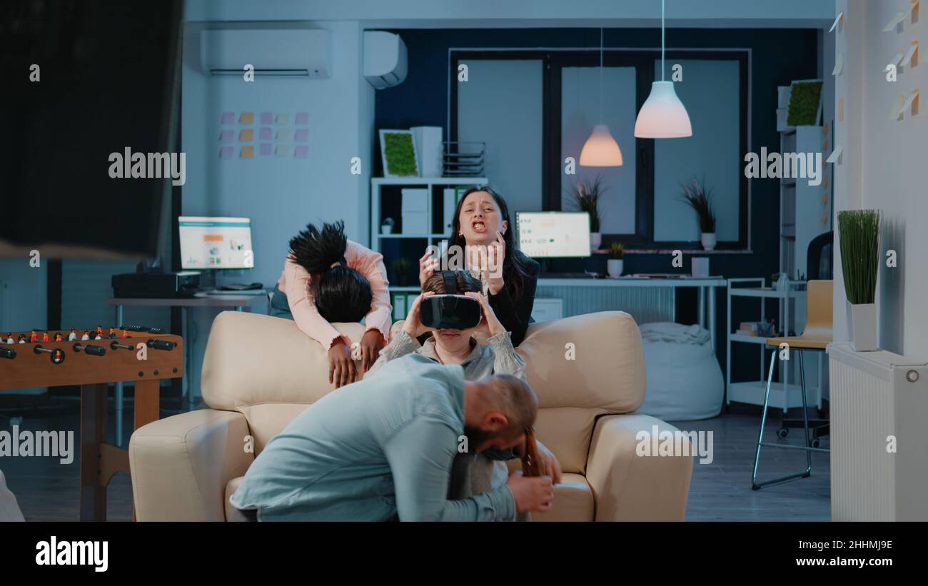 Colleagues enjoying drinks and video games on television after work ...