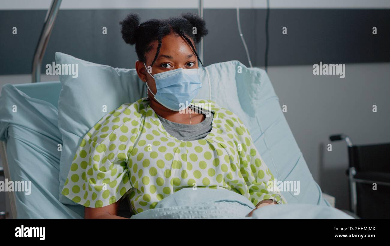 Portrait of young patient with sickness wearing face mask in hospital ...