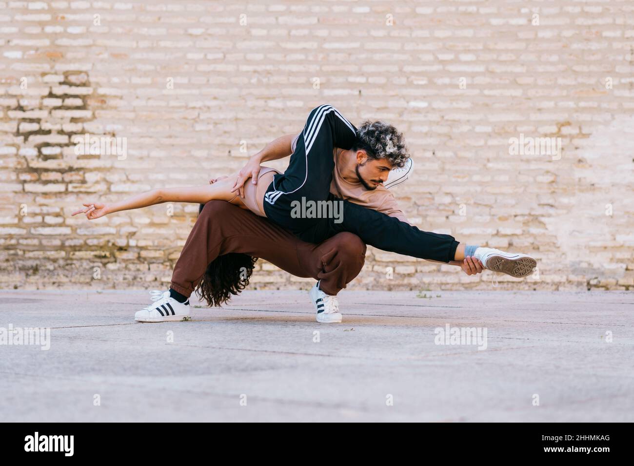 Lovely young Spanish couple dancing against a brick wall outdoors Stock ...