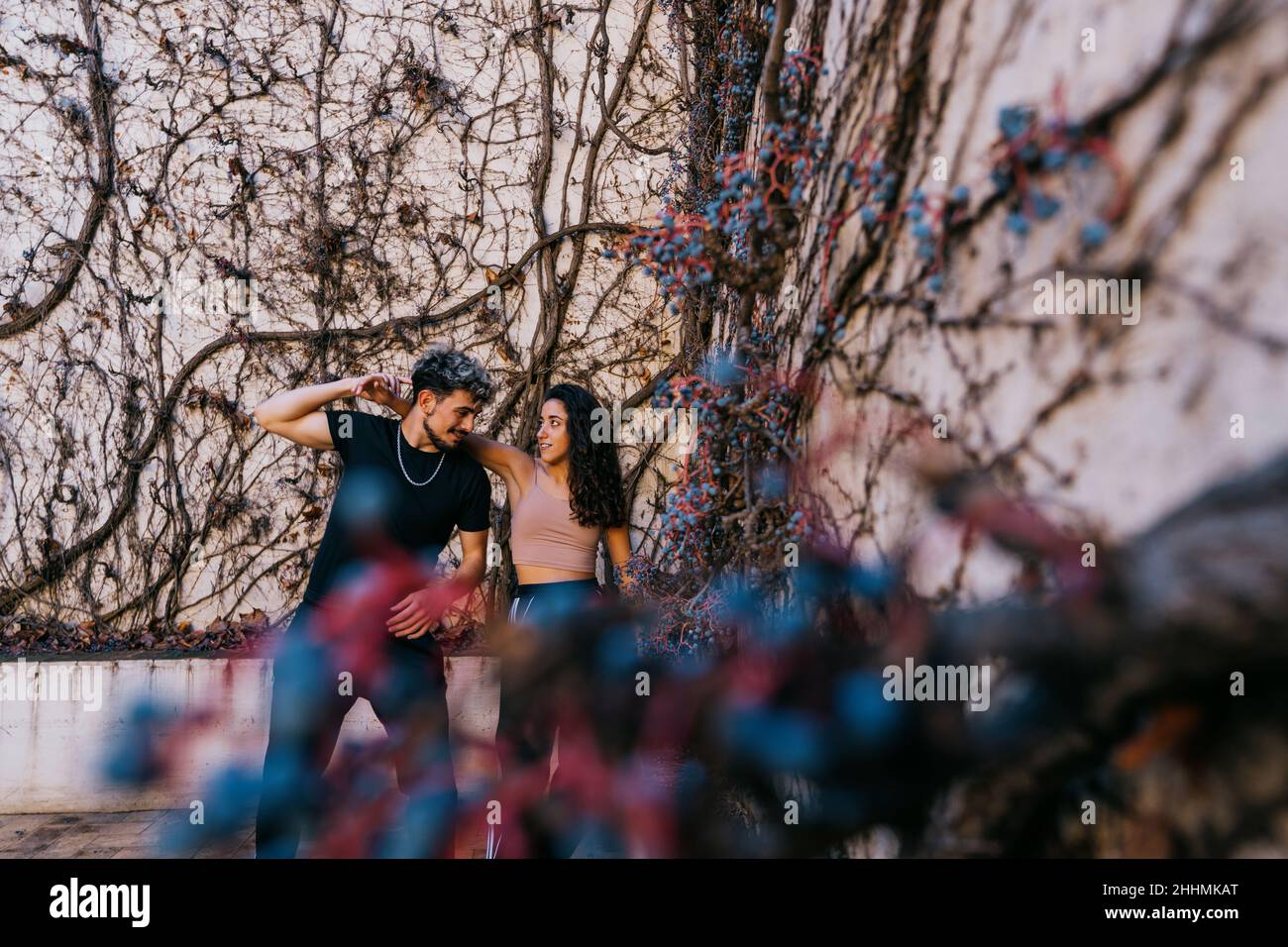 Adorable young Spanish couple cuddling in a garden covered in creeping ...
