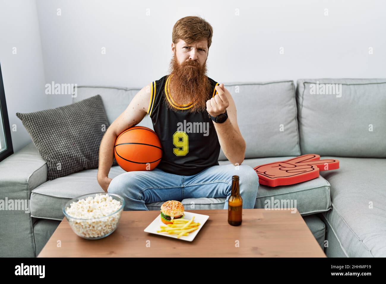 Caucasian man with long beard holding basketball ball cheering tv game ...