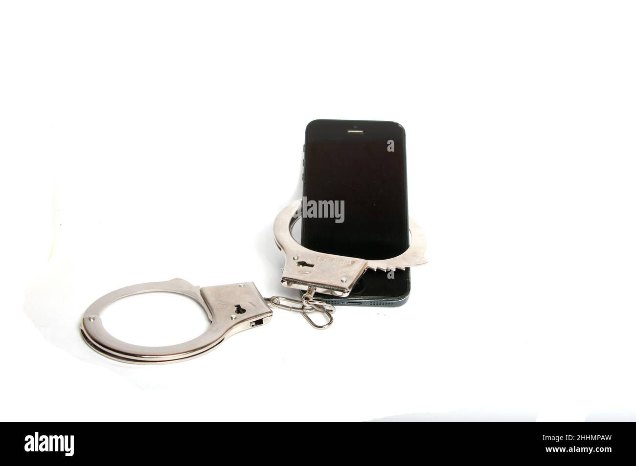 Phone in handcuffs on white background Stock Photo - Alamy