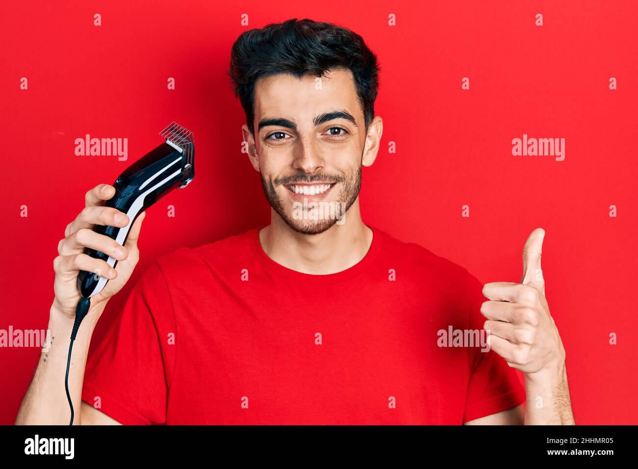 Young hispanic man charging electric razor machine smiling happy and ...