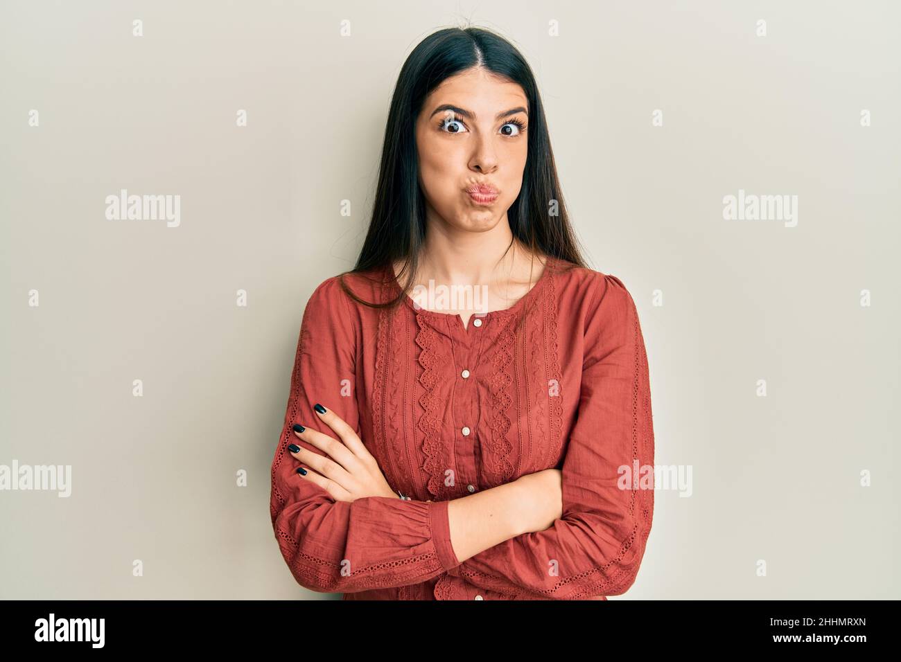 Young hispanic woman wearing casual clothes puffing cheeks with funny face. mouth inflated with ...