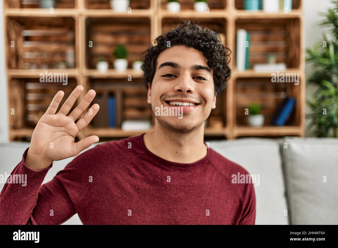 Young hispanic man smiling happy saying hello with hand at home Stock ...