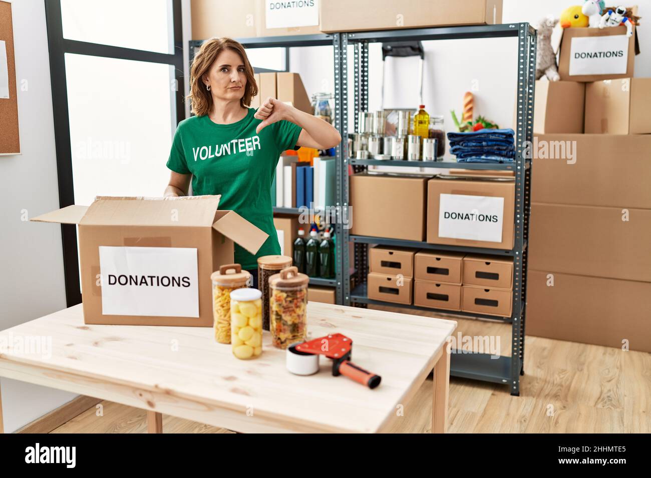 Middle age woman wearing volunteer t shirt at donations stand with ...