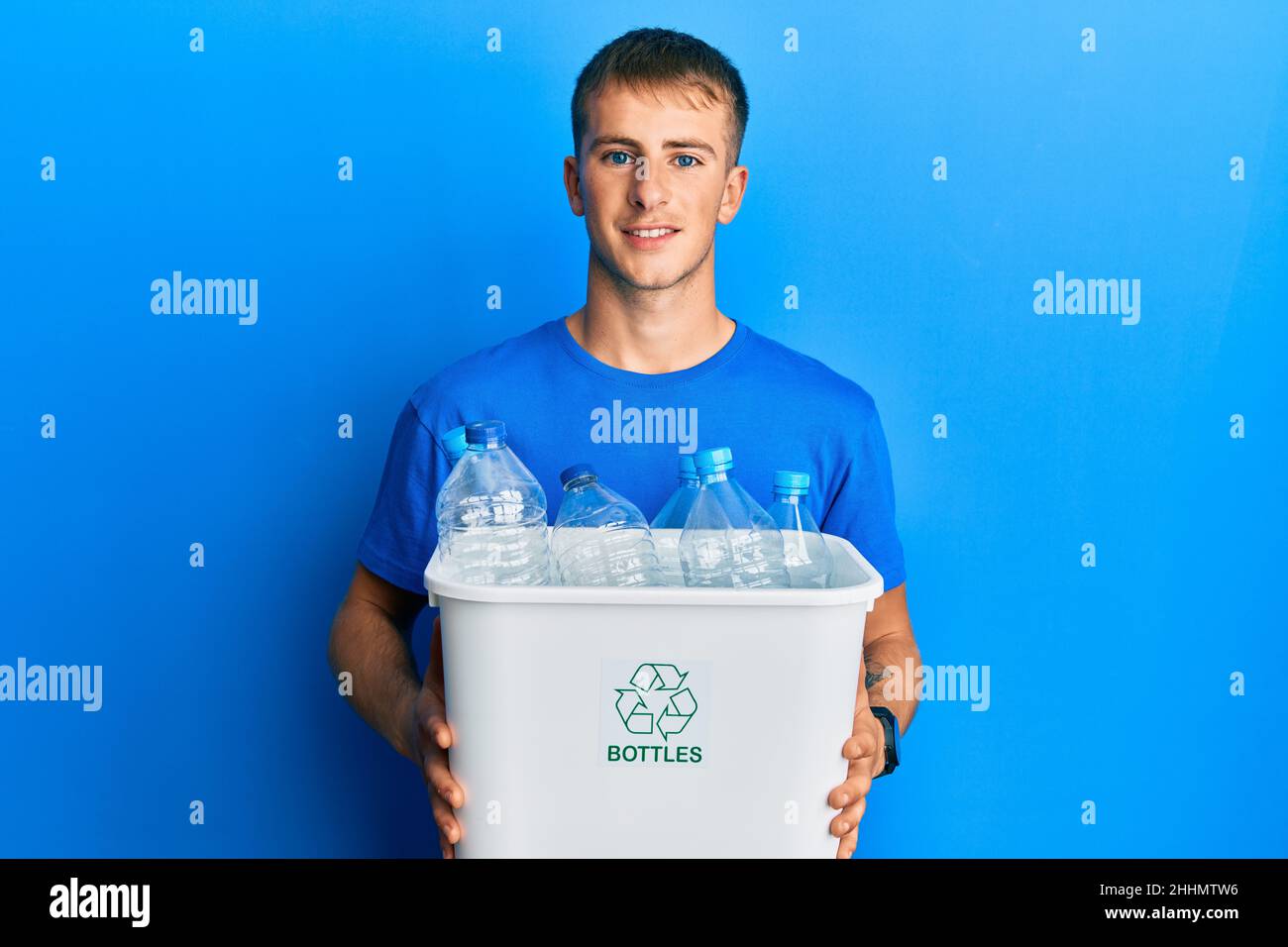 Young caucasian man holding recycling wastebasket with plastic bottles ...