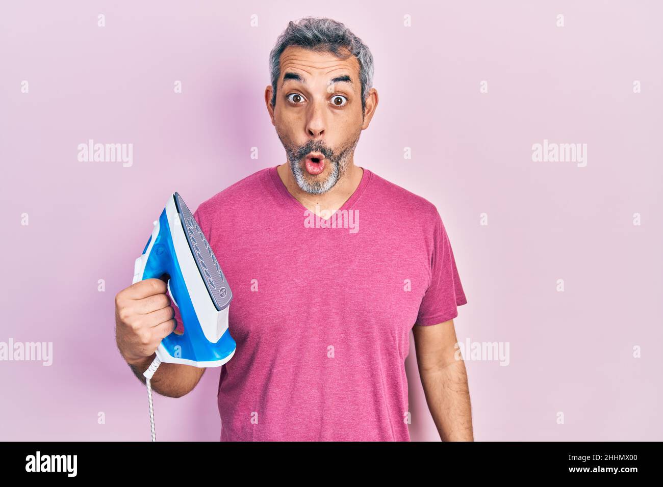 Handsome middle age man with grey hair holding electric steam iron ...