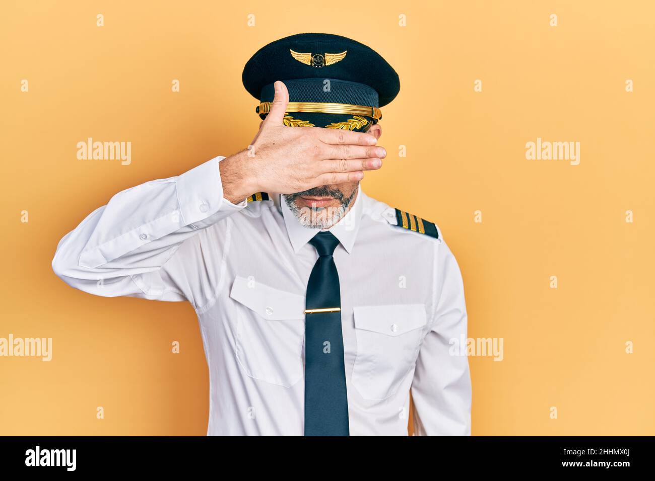 Handsome middle age man with grey hair wearing airplane pilot uniform ...